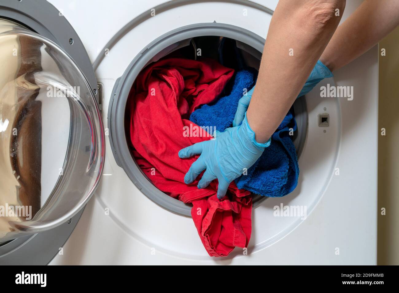 Loading bed linen into a household washing machine Stock Photo - Alamy