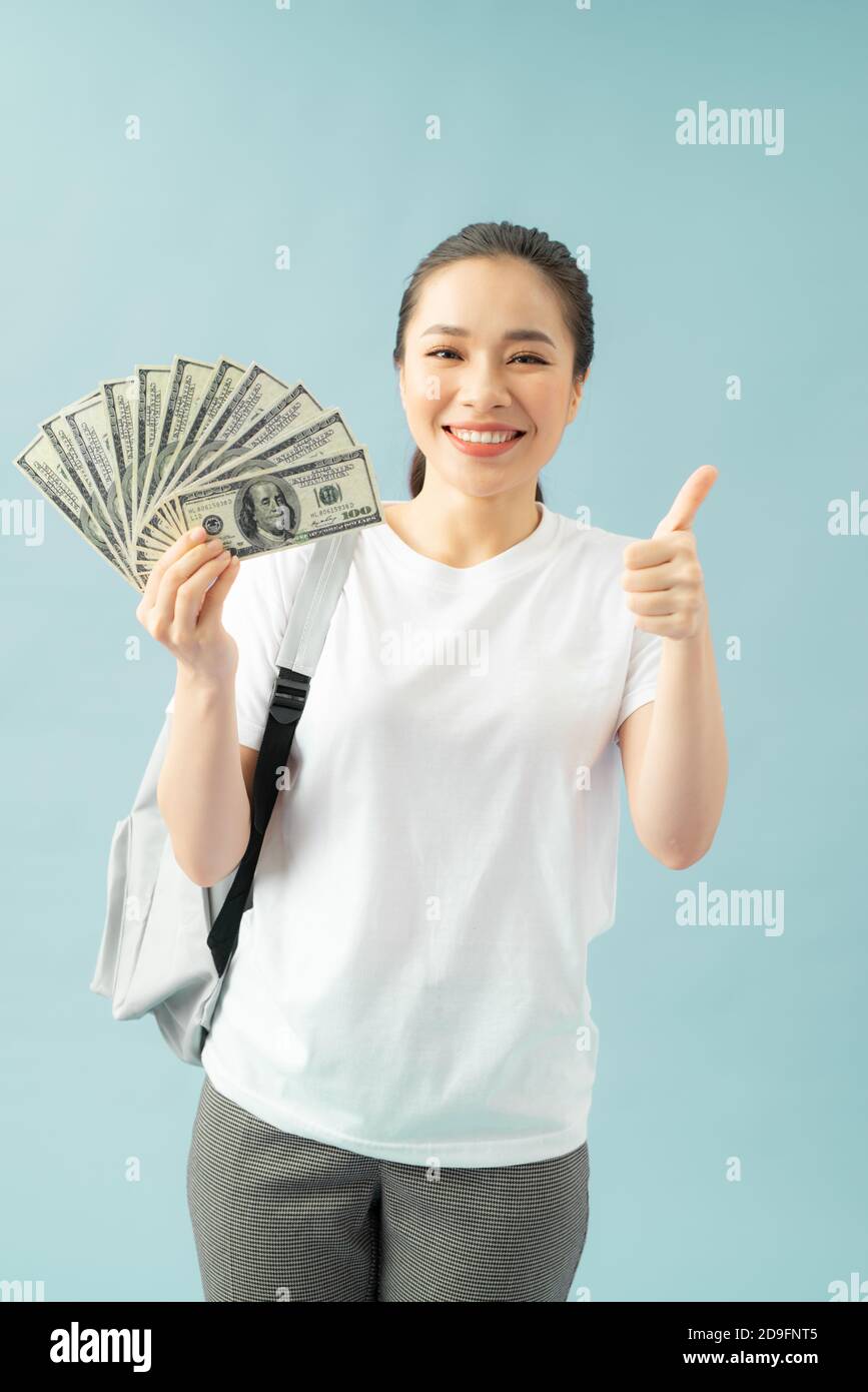 Funny girl student wearing backpack isolated, holding fan of cash money ...