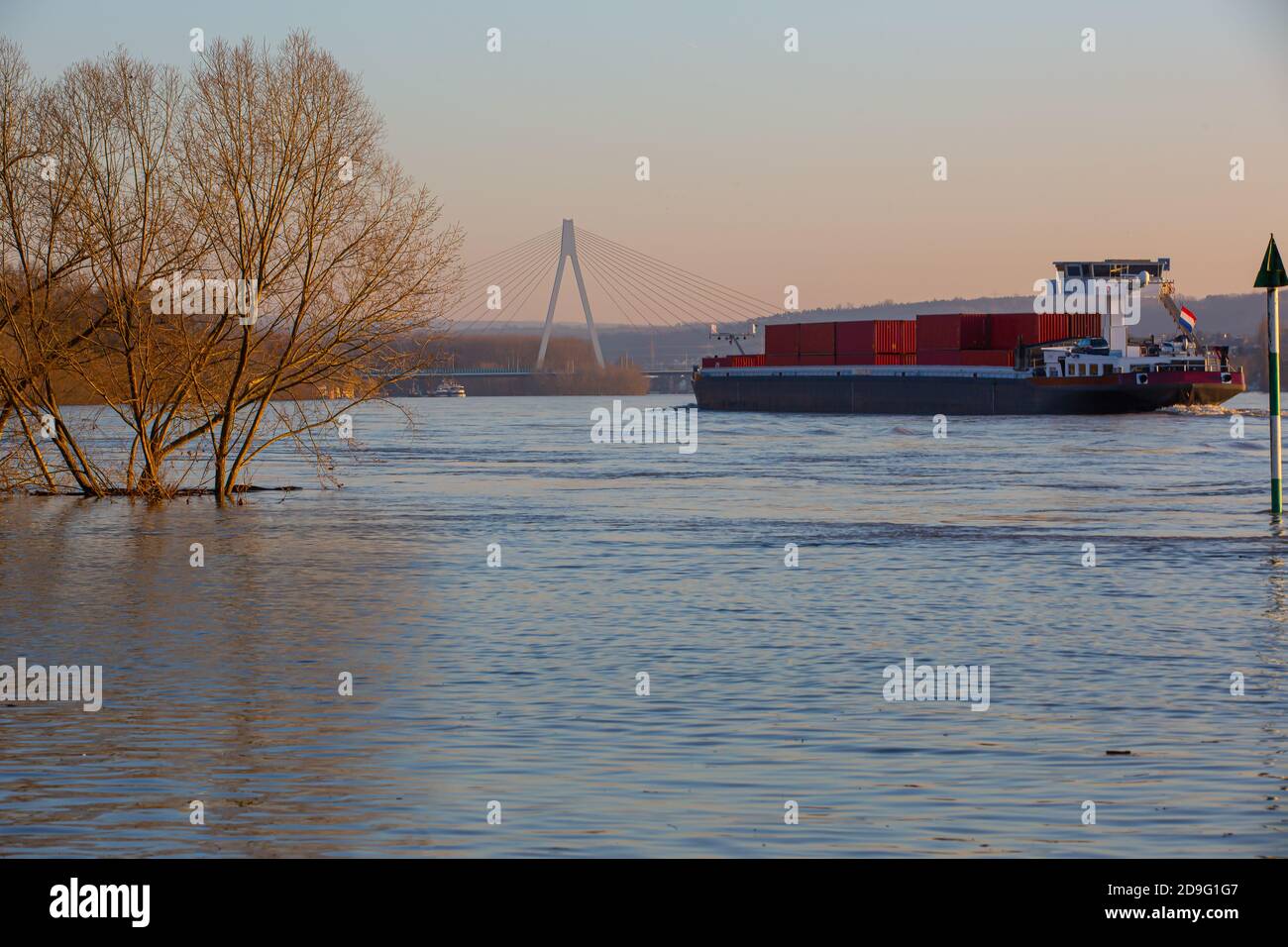 A river barge with containers on the river Rhine with a bridge in the ...