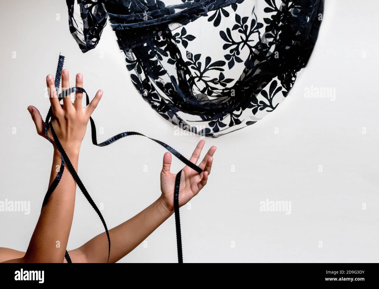 Closeup shot of hands holding string and lacy fabric on a white ...