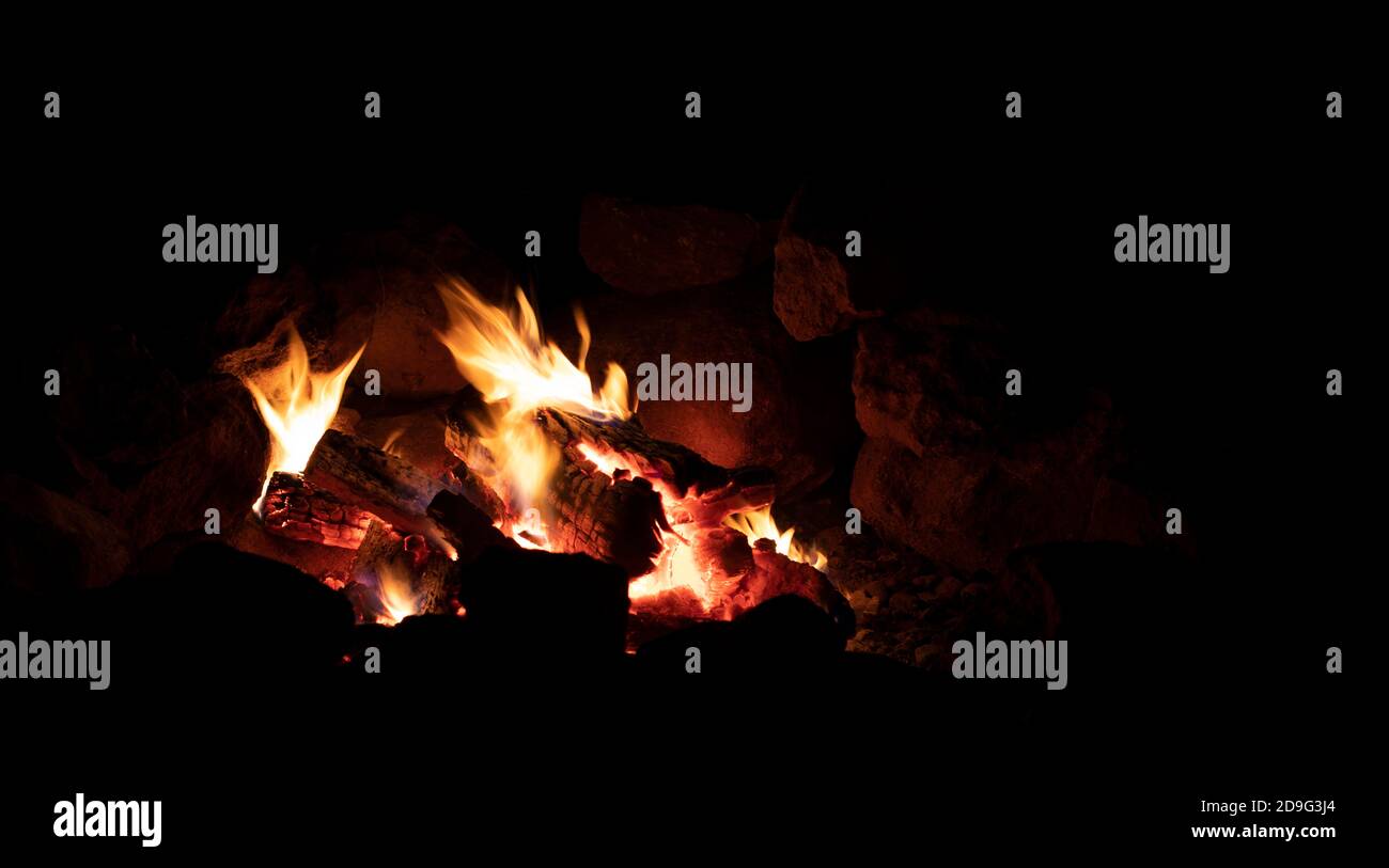 Campfire at night being blown to the left by a breeze Stock Photo - Alamy