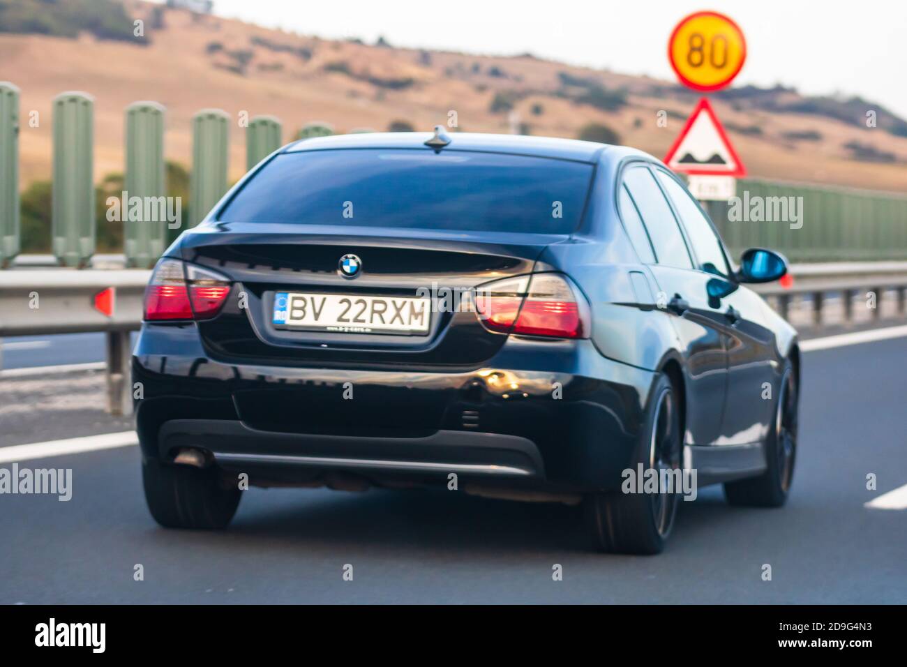 Traveling black car in motion on asphalt road, back view of car on ...