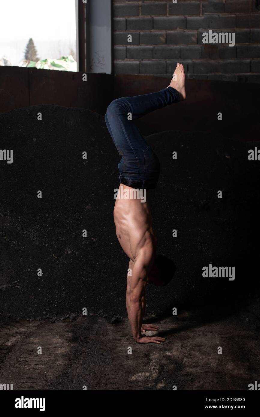 Young Man Keeping Balance on Hands in Warehouse - Muscular Athletic ...