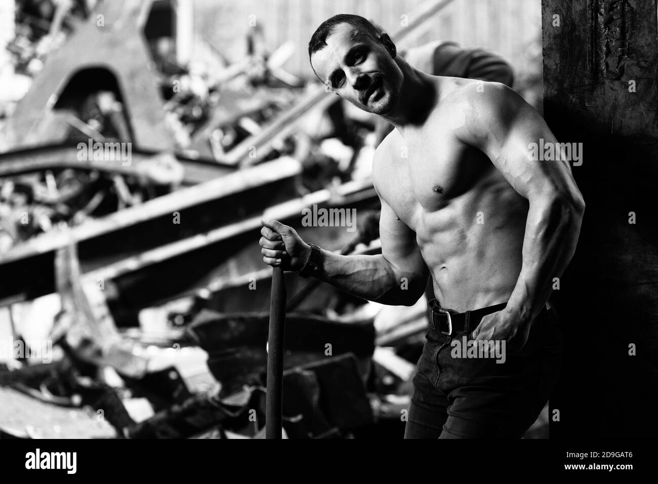Young Man Standing Strong in Old Scrap Metal Garage and Flexing Muscles ...