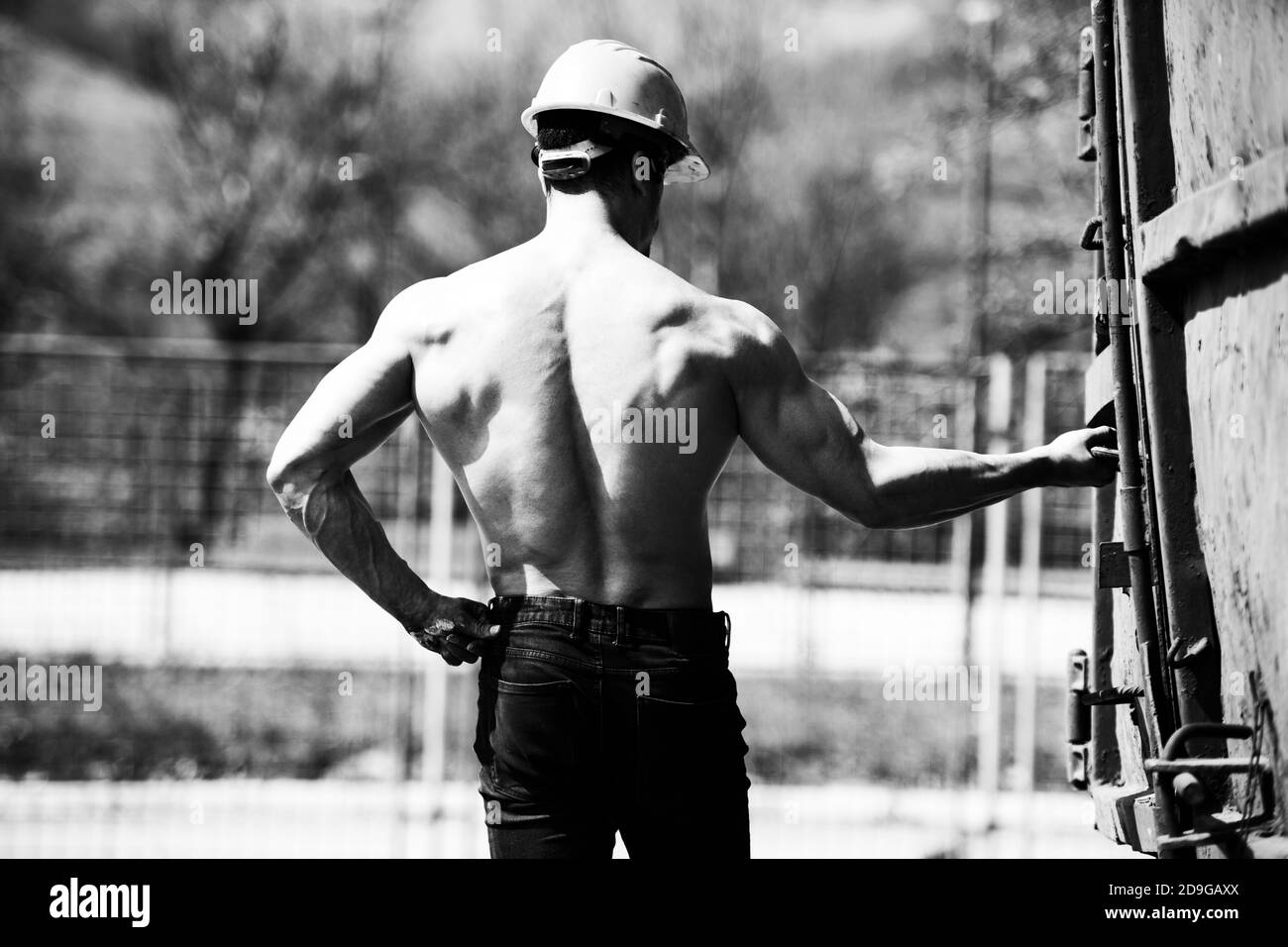 Young Man Standing Strong in Old Scrap Metal Garage and Flexing Muscles ...