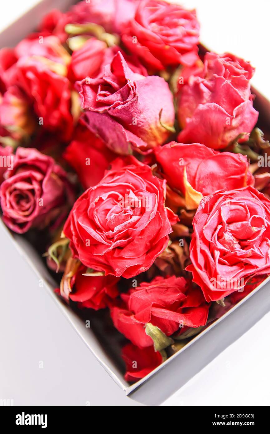 Red rose dried buds, flowers and petals in the opened cardboard box ...