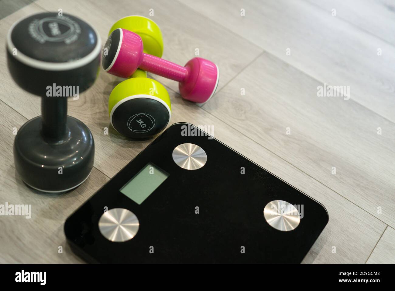 Dumbbells and modern scales on the floor in a room Stock Photo - Alamy