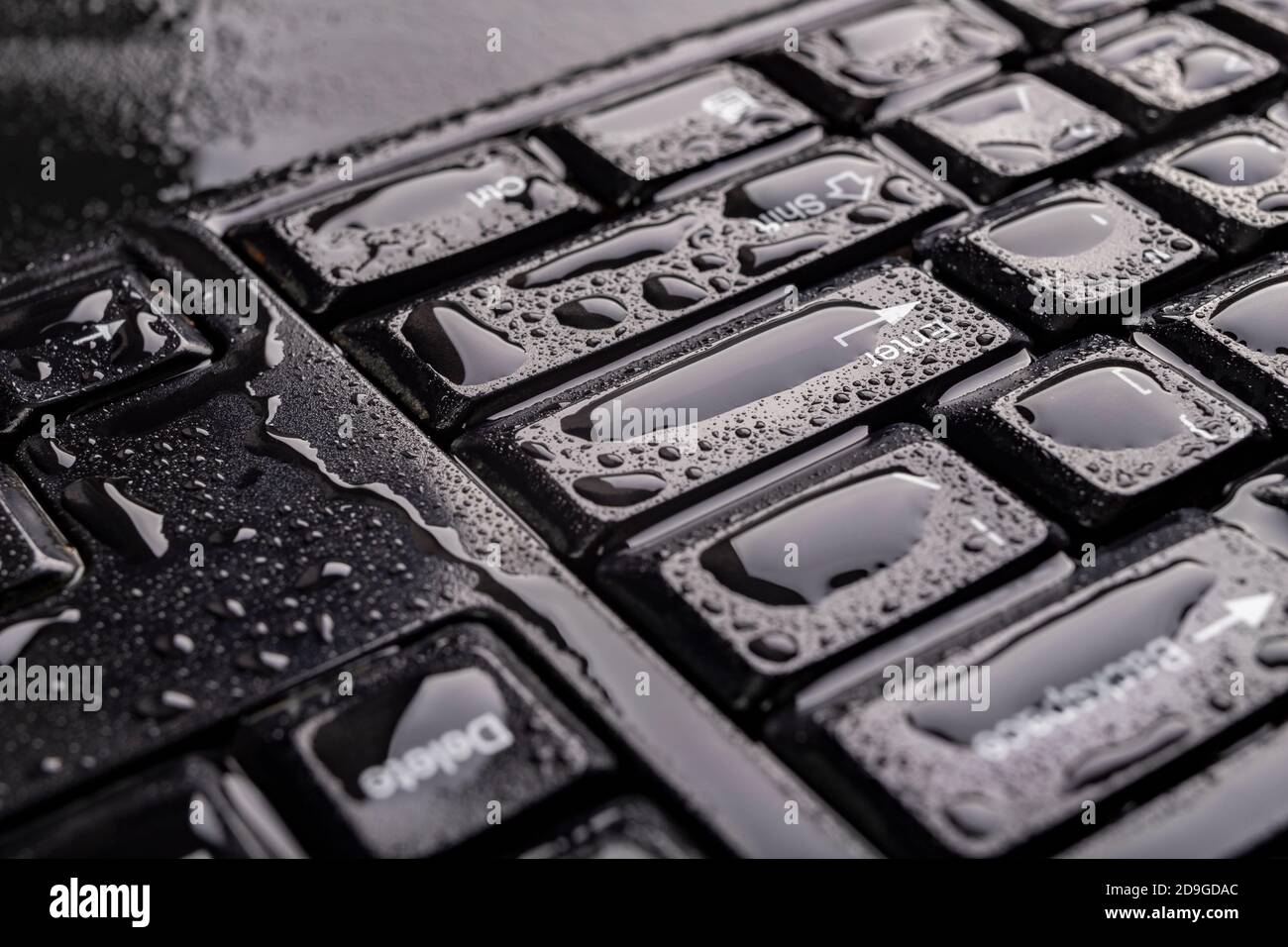 Water drops on the computer keyboard. Water flooded computer keys. Dark ...