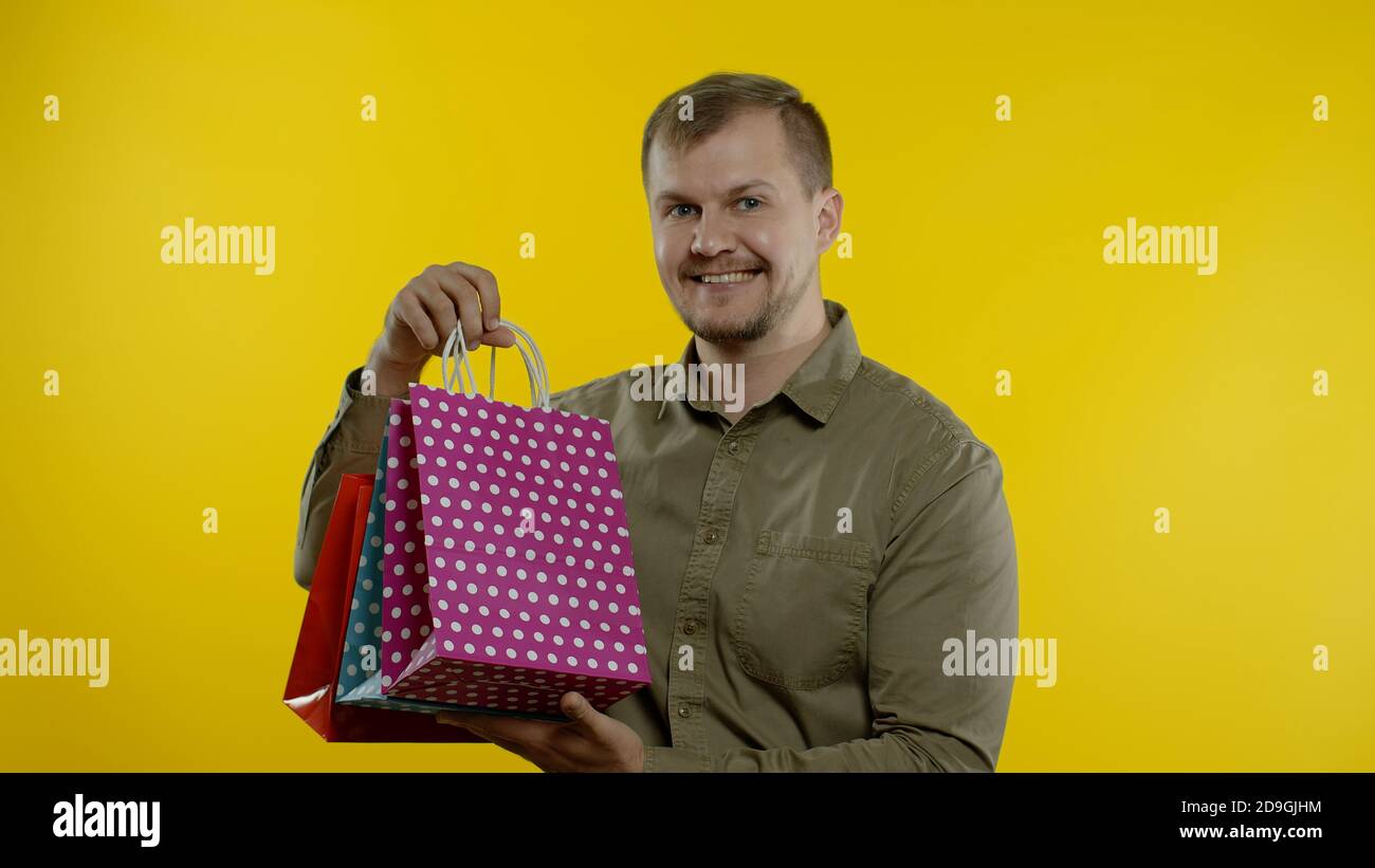 Joyful man showing Black Friday inscription from shopping bags, smiling ...