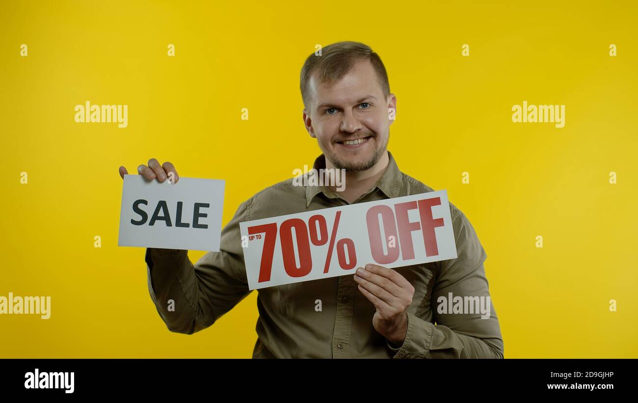 Great discounts. Happy joyful blonde man showing Sale word and showing ...