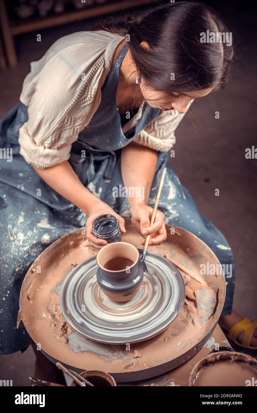 Master-ceramist creates a clay pot on a potter's wheel. Hands of potter ...