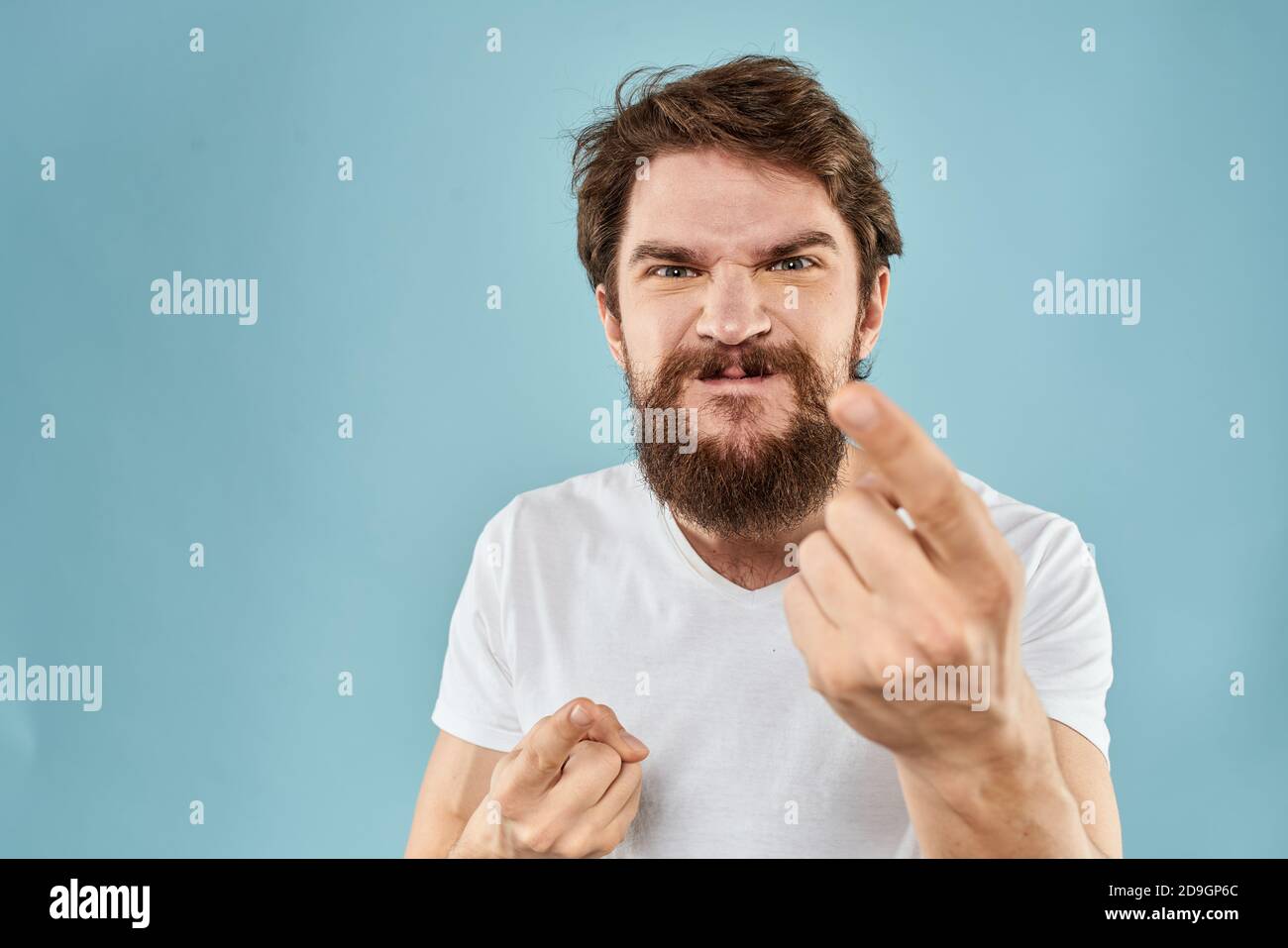 Bearded man in white T-shirt emotions gestures with hands displeased ...