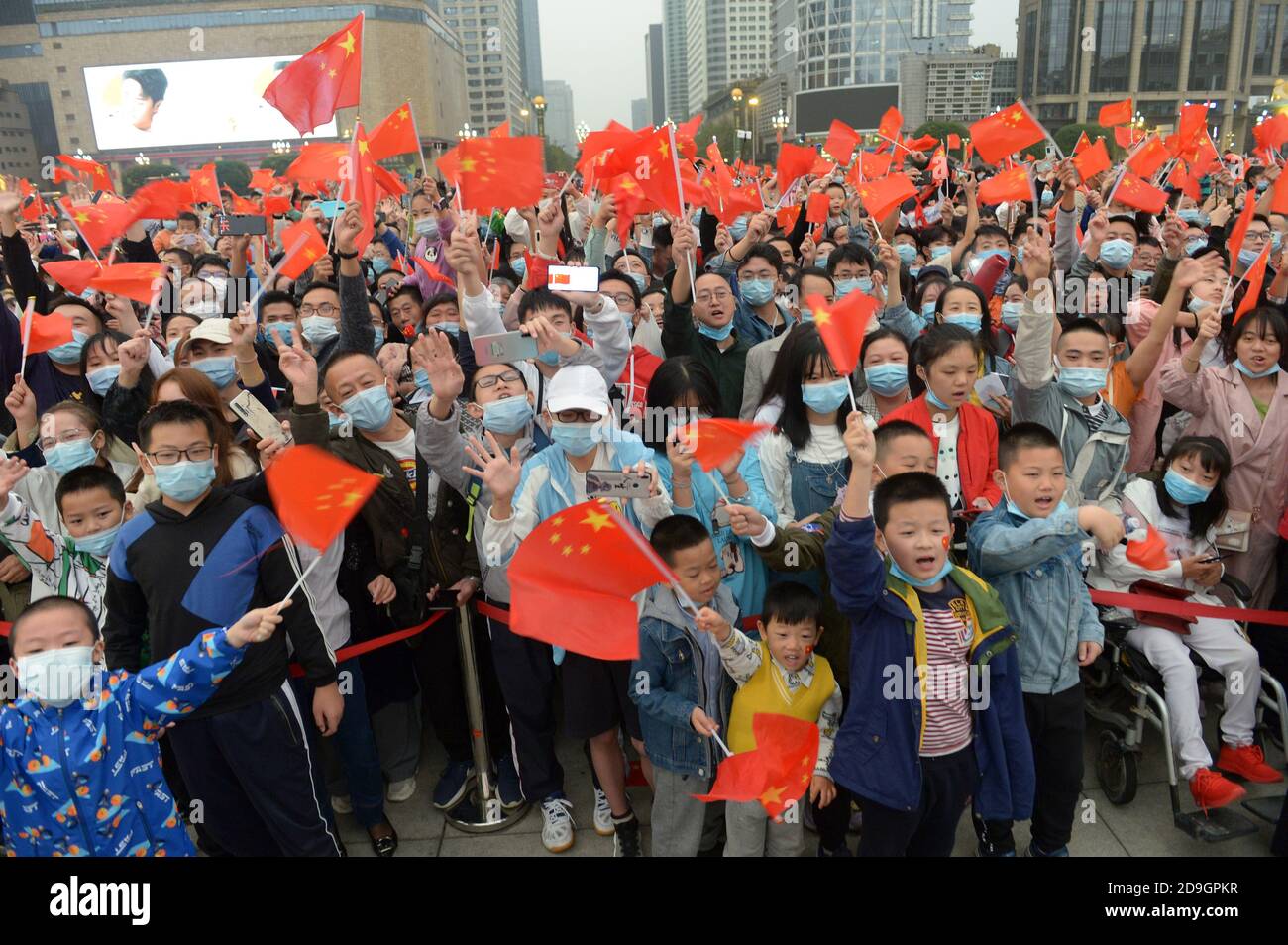 People wave Chinese flags while watching the Chinese flag raising ...