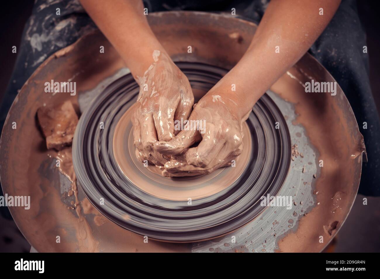 Hands of the master potter and vase of clay on the potter's wheel close ...