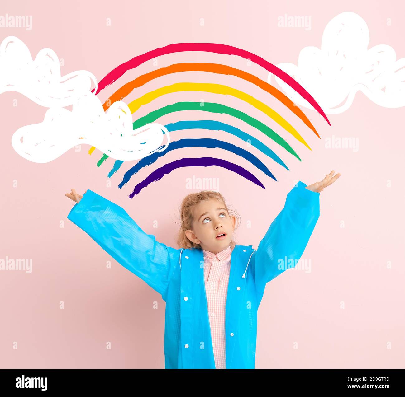 Cute little girl in raincoat on color background with drawn rainbow and ...