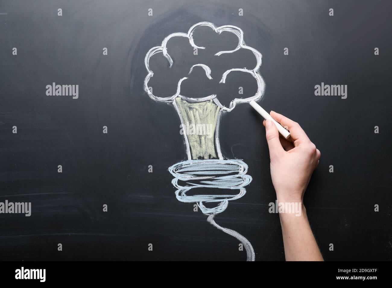 Female hand drawing lightbulb on chalkboard Stock Photo - Alamy