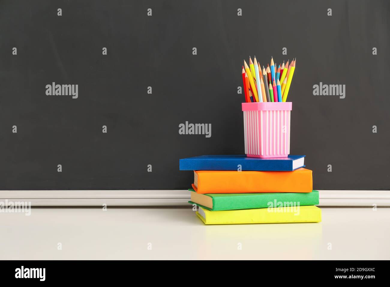 Holder with pencils and books on table in classroom Stock Photo - Alamy