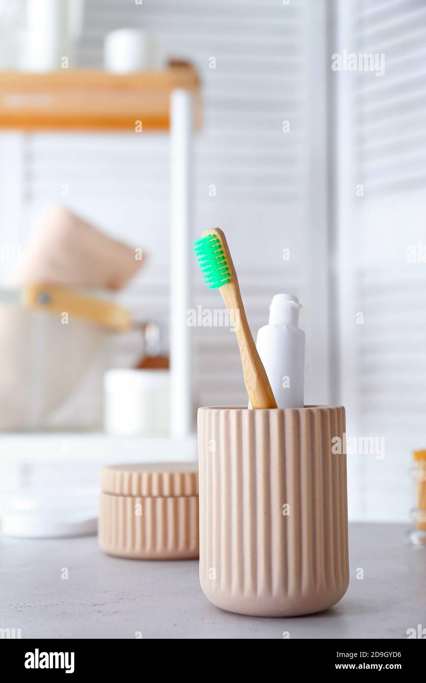 Cup with tooth brush and paste in bathroom Stock Photo - Alamy