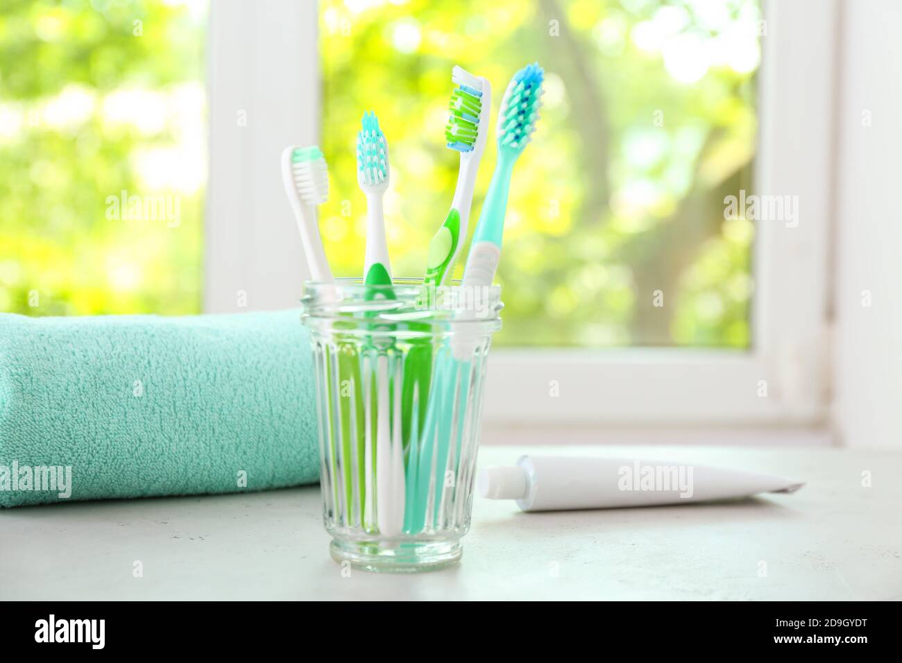Cup with tooth brushes on table in bathroom Stock Photo - Alamy