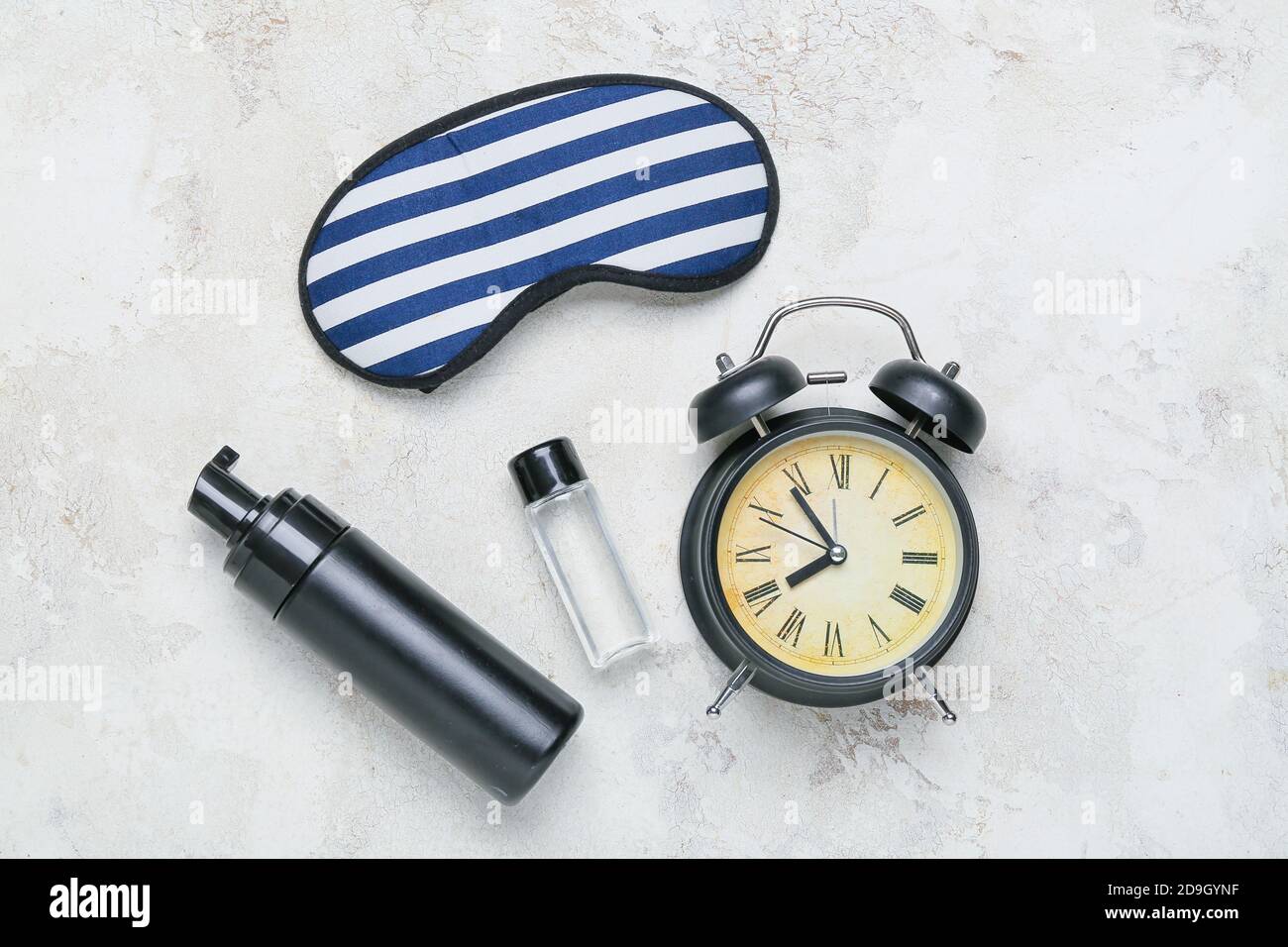 Sleeping mask, alarm clock and cosmetics on light background Stock ...