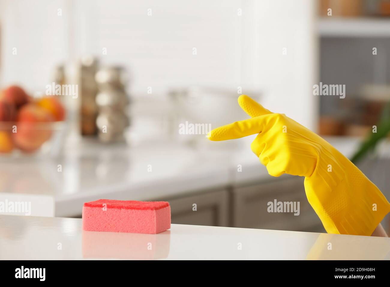 Hand of woman in rubber glove pointing at sponge on kitchen counter ...