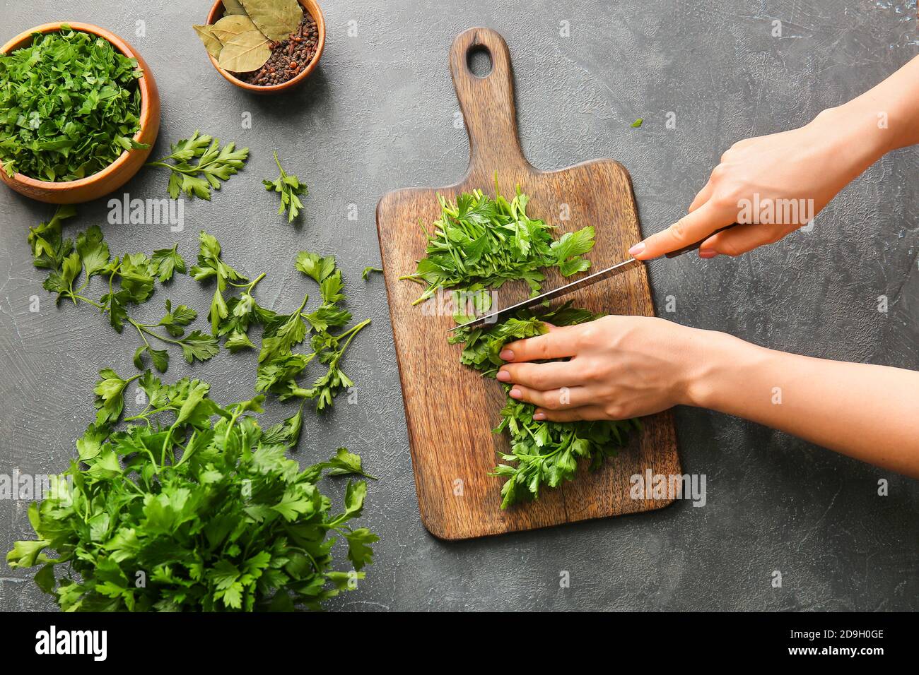 Woman cutting fresh parsley at table Stock Photo - Alamy