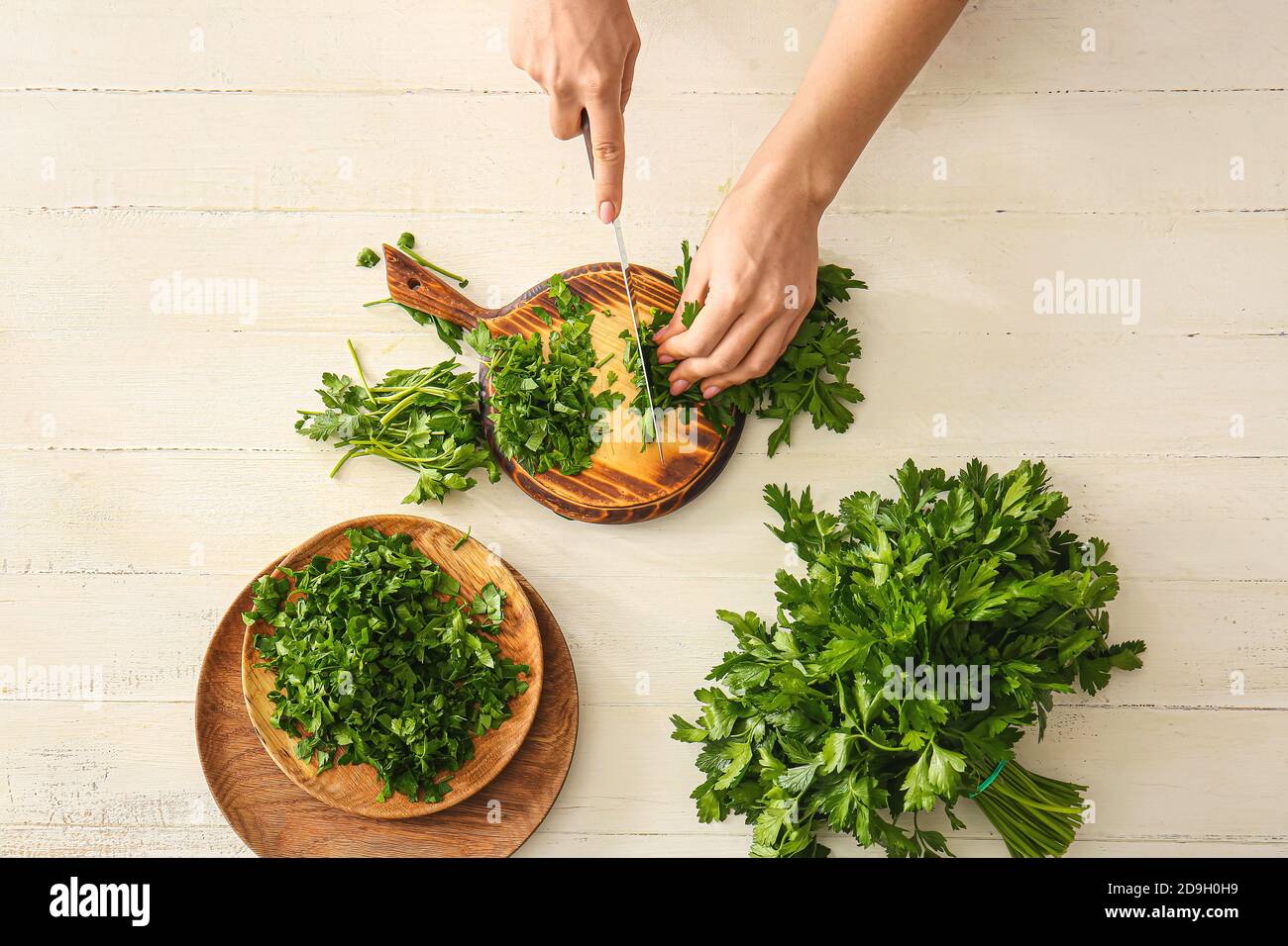 Woman cutting fresh parsley at table Stock Photo - Alamy