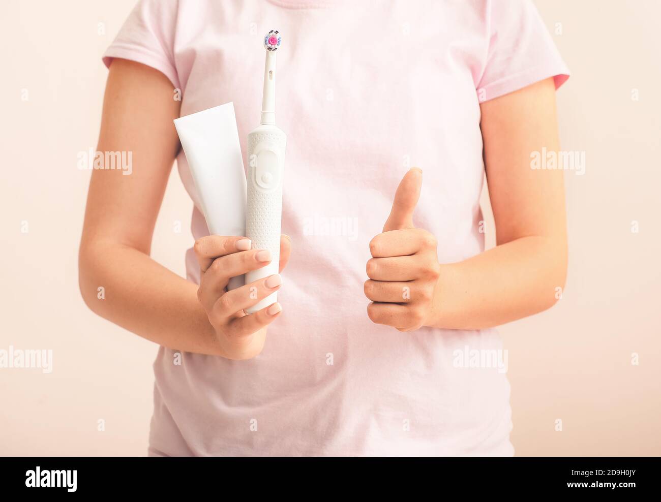 Woman with tooth brush and paste showing thumb-up on light background ...