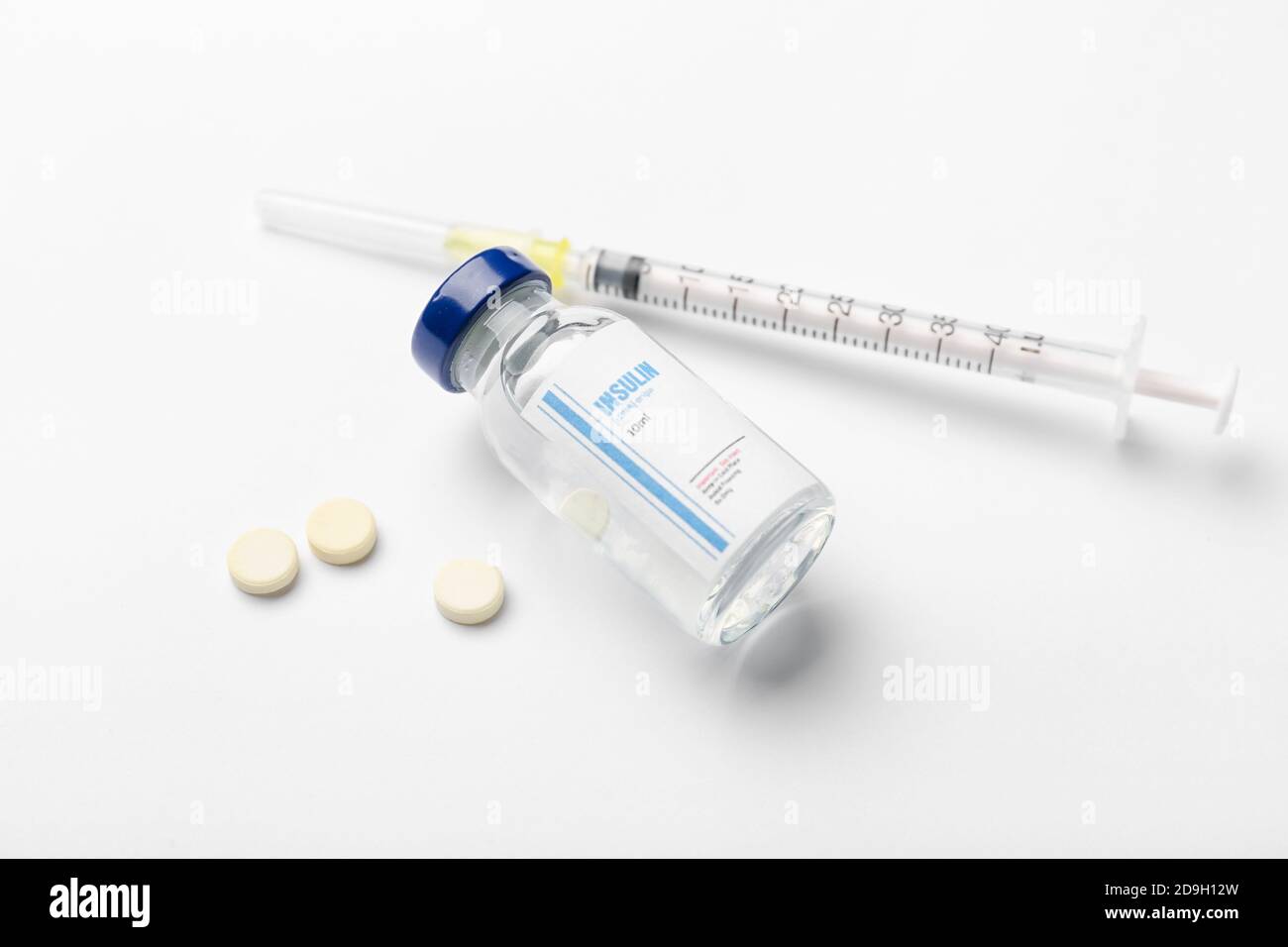 Bottle of insulin with syringe and pills on white background. Diabetes ...