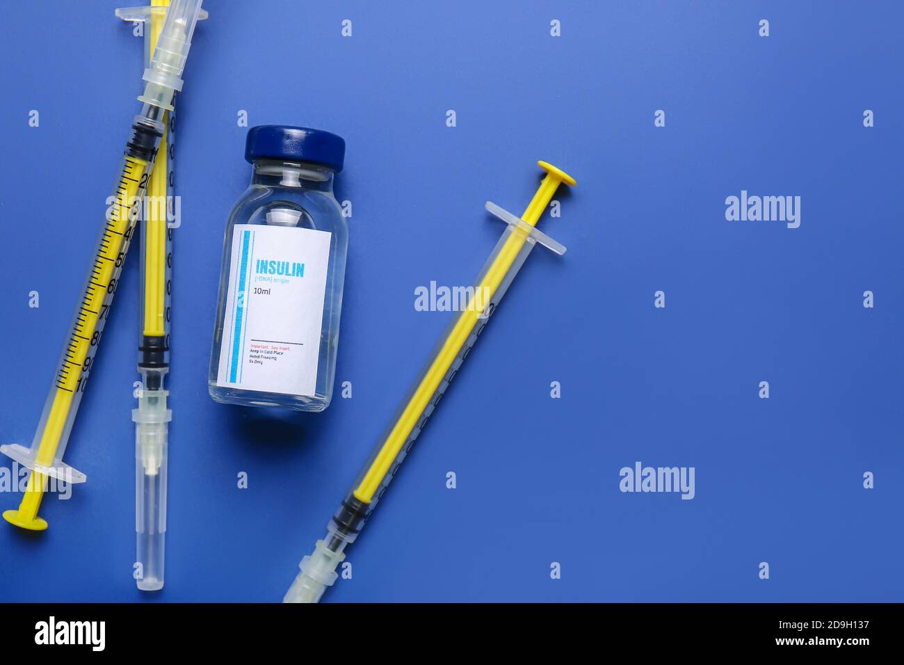 Bottle of insulin with syringes on color background. Diabetes concept ...