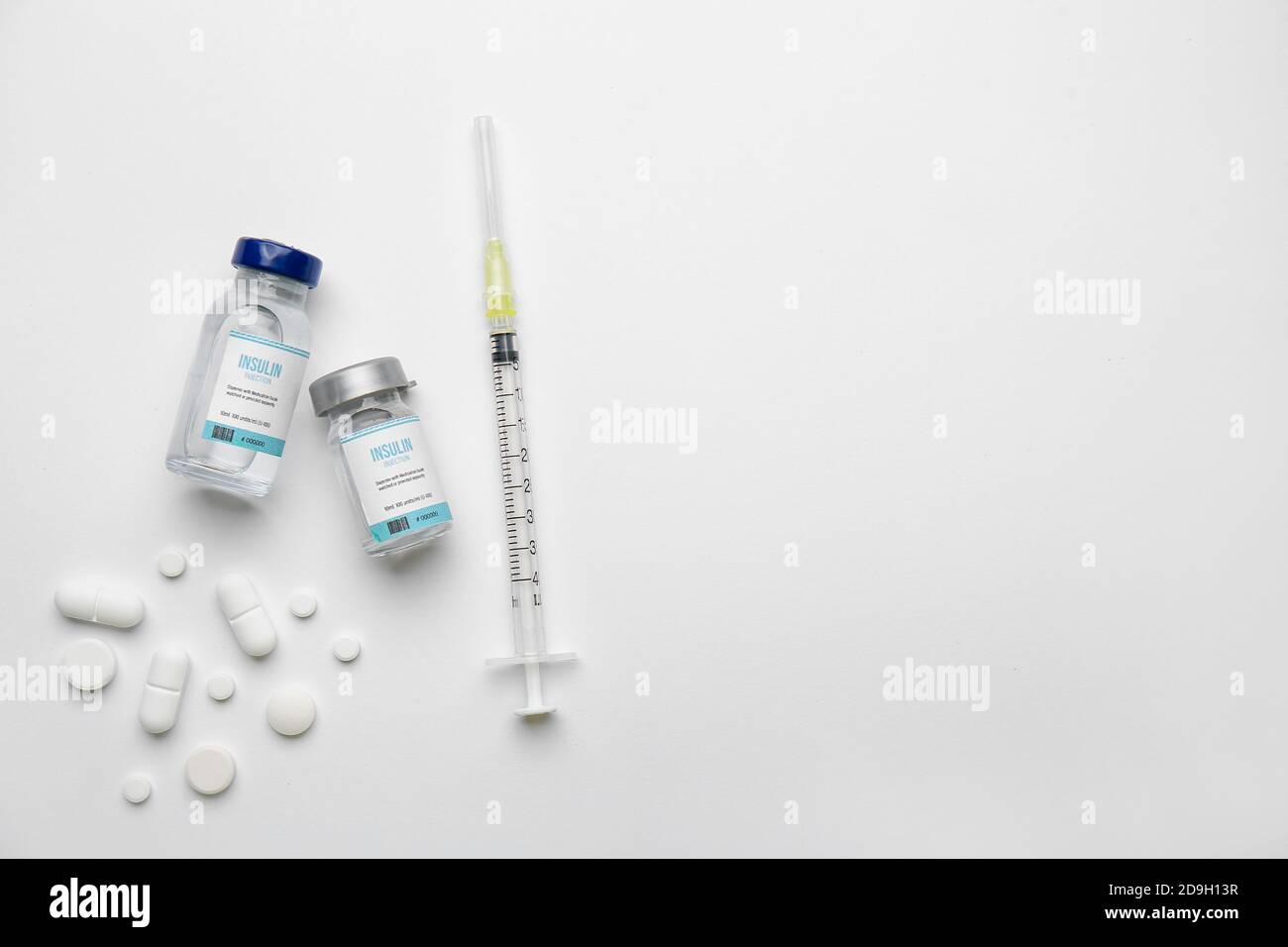 Bottles of insulin with syringe and pills on white background. Diabetes ...