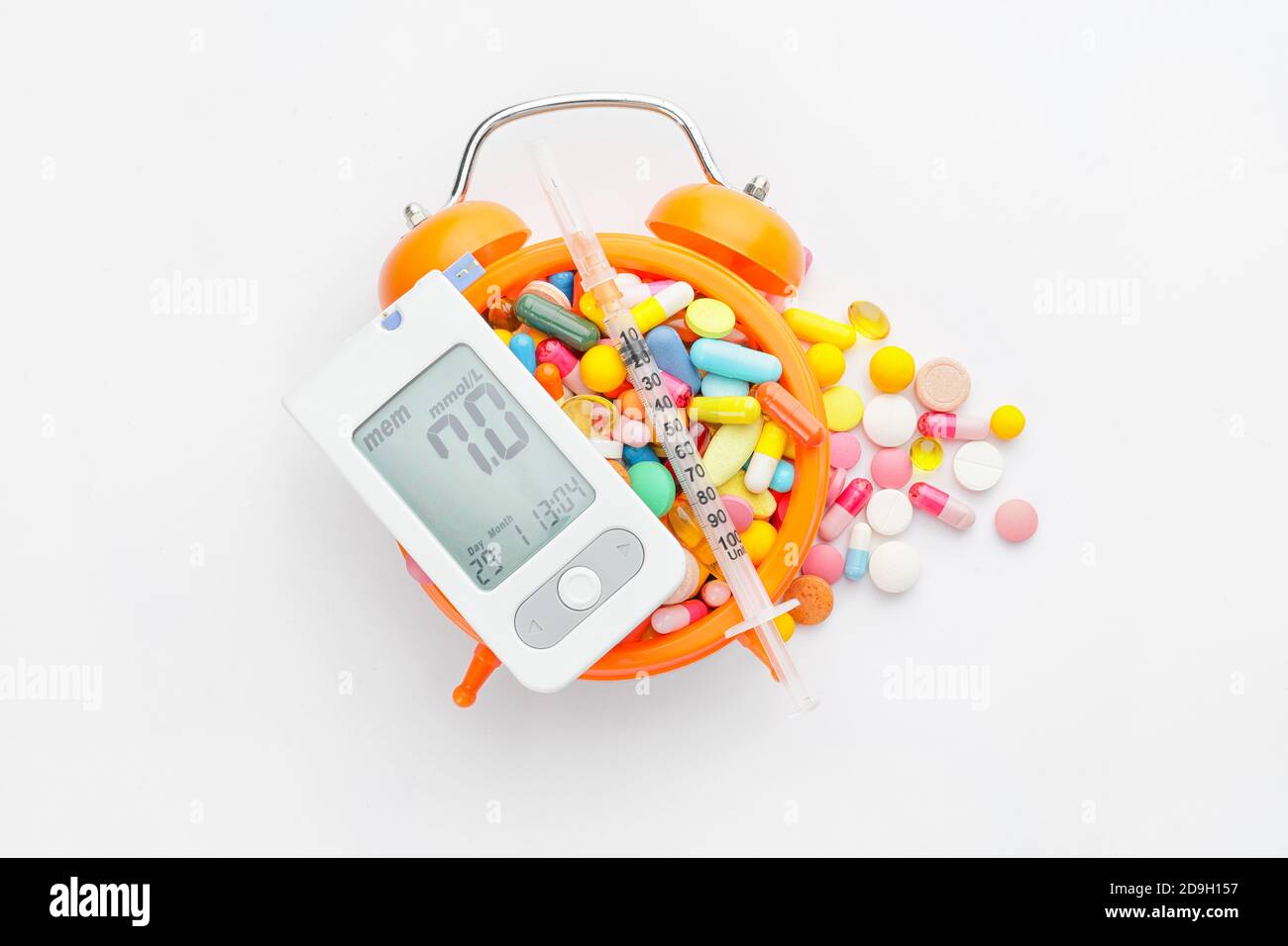 Glucometer, alarm clock, pills and syringe on white background ...