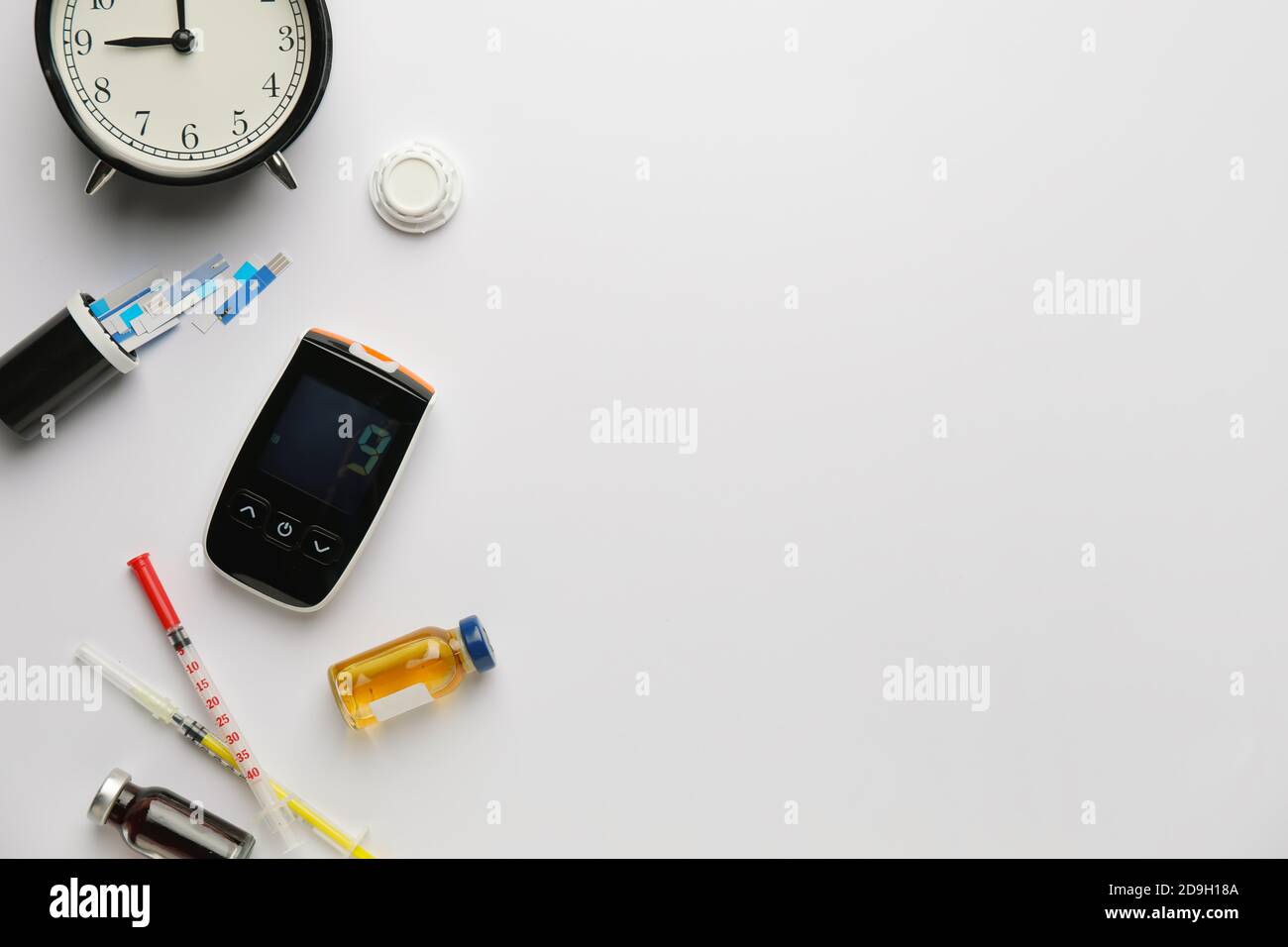 Glucometer, test strips, alarm clock, bottle of insulin and syringes on ...