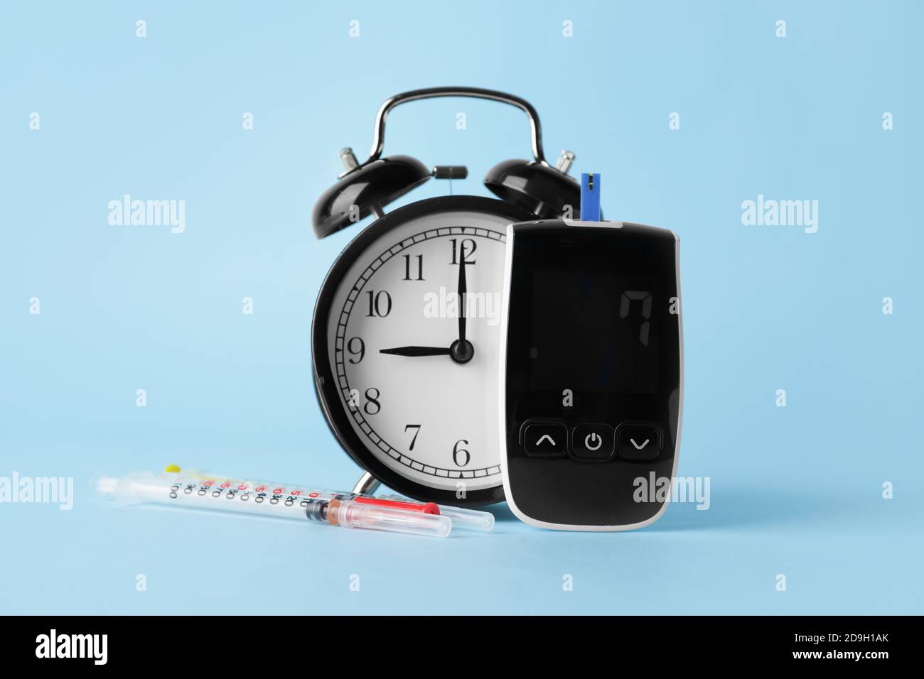 Glucometer with alarm clock and syringes on color background. Diabetes ...