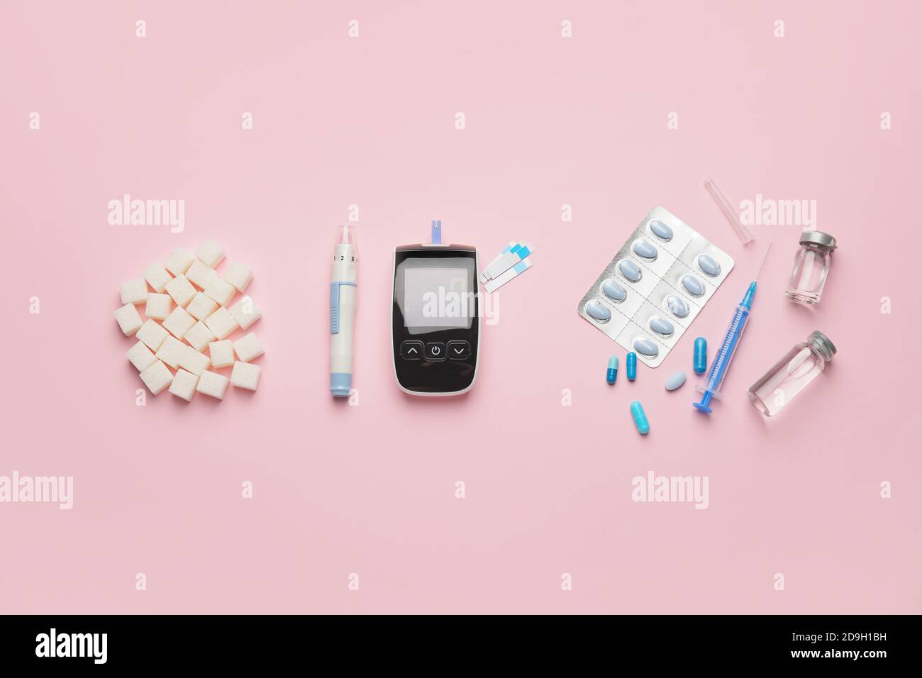 Glucometer with sugar cubes, medications, lancet pen and syringe on ...