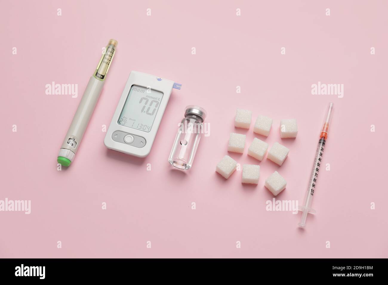 Glucometer with sugar cubes, bottle of insulin and syringes on color ...
