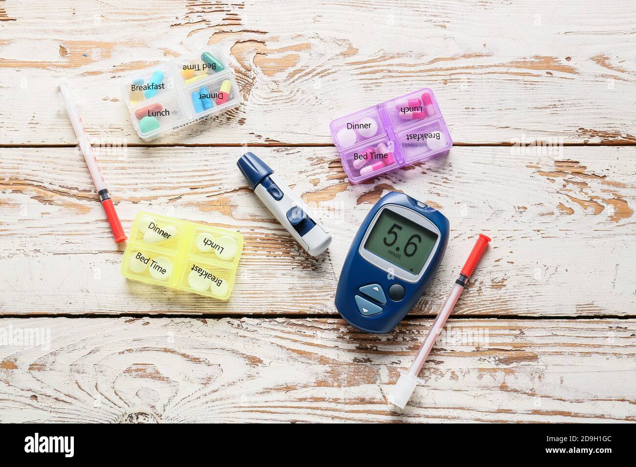 Glucometer with lancet pen, syringes and pills on white wooden ...