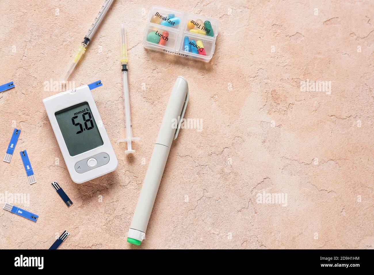Glucometer with lancet pen, test strips, syringes and pills on color ...