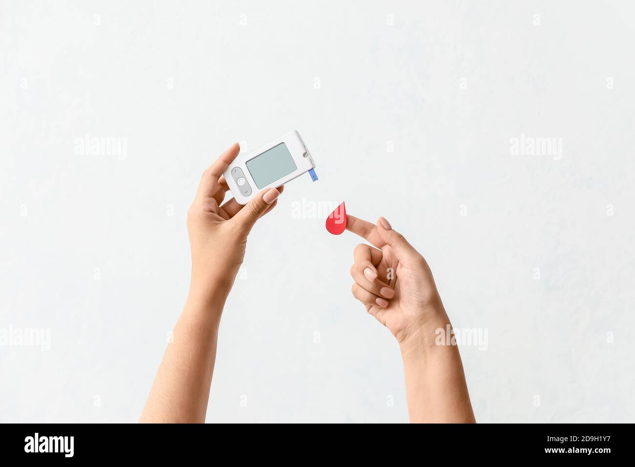 Female hands with glucometer and blood drop on light background ...