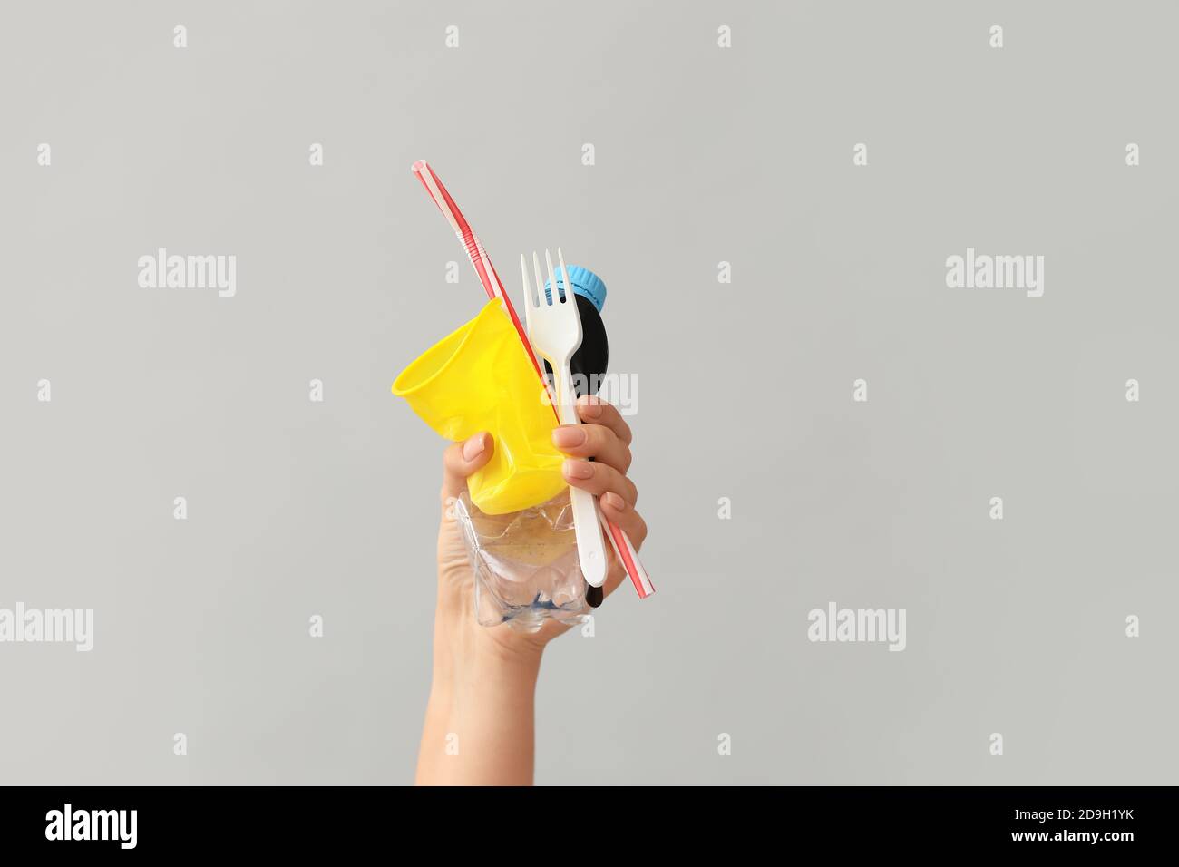Female hand with plastic garbage on grey background. Ecology concept ...
