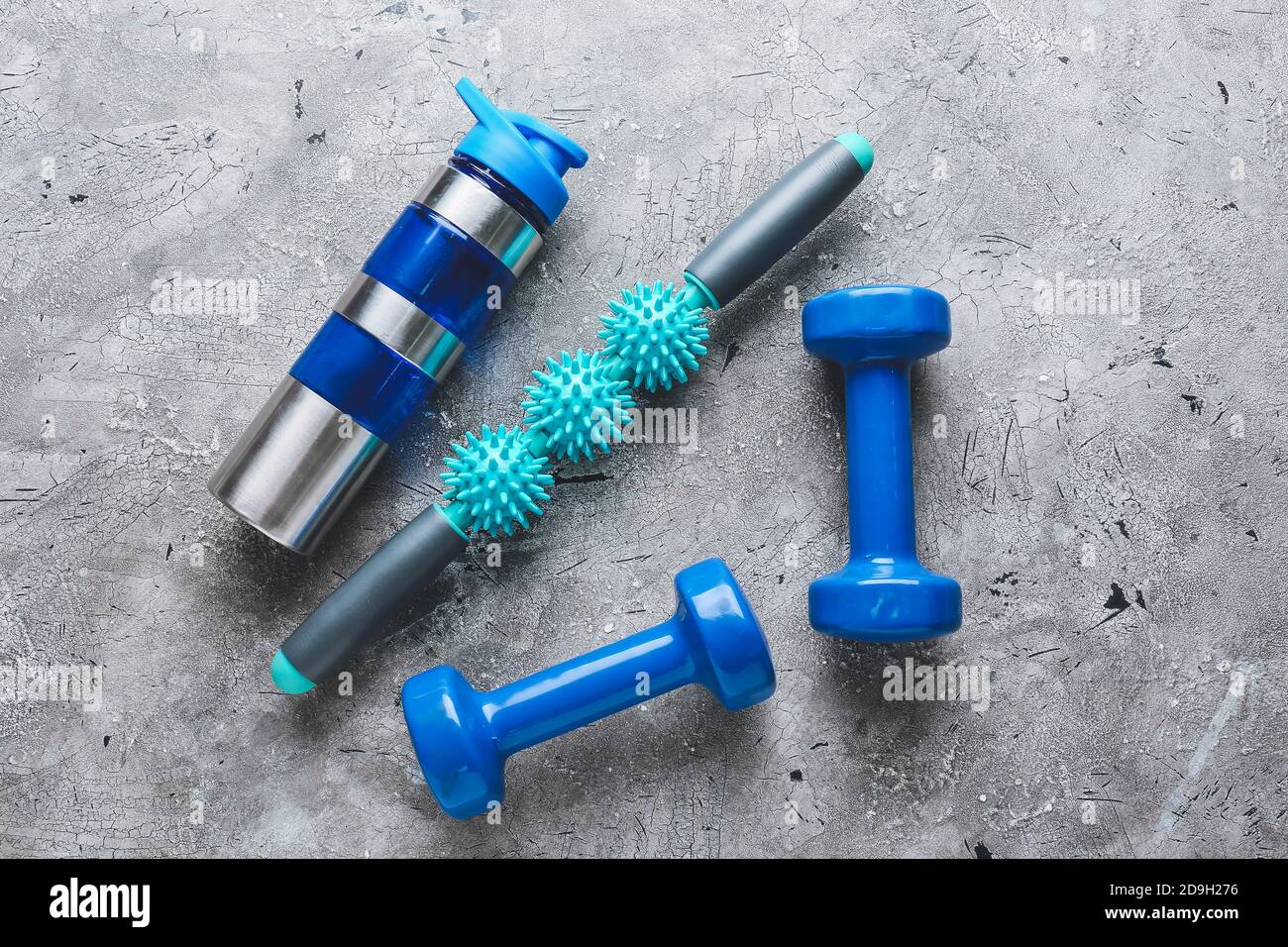 Body roller with dumbbells and bottle of water on grunge background ...
