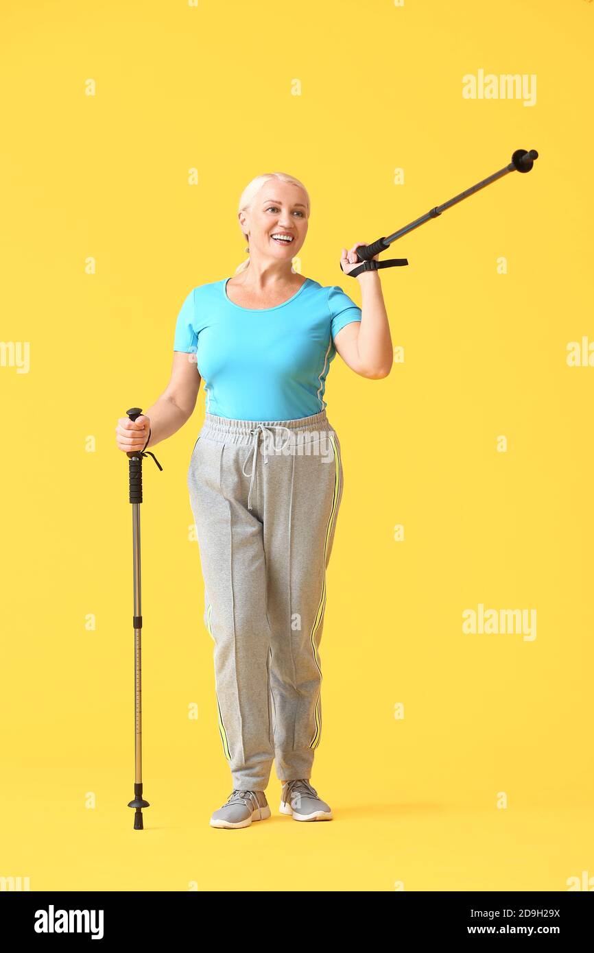 Mature woman with walking poles on color background Stock Photo - Alamy