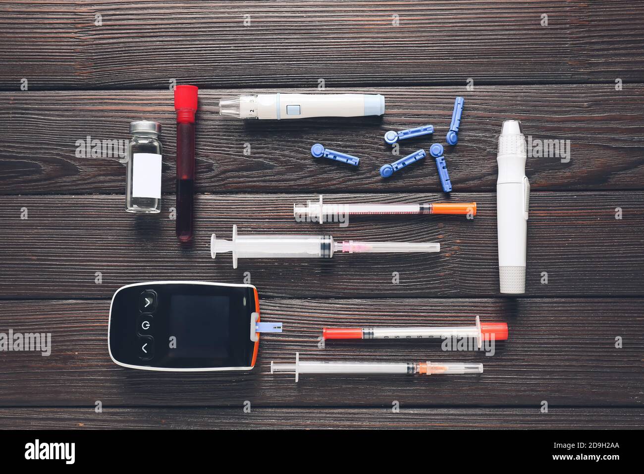 Glucometer, lancet pens, blood sample, syringes and insulin on wooden ...