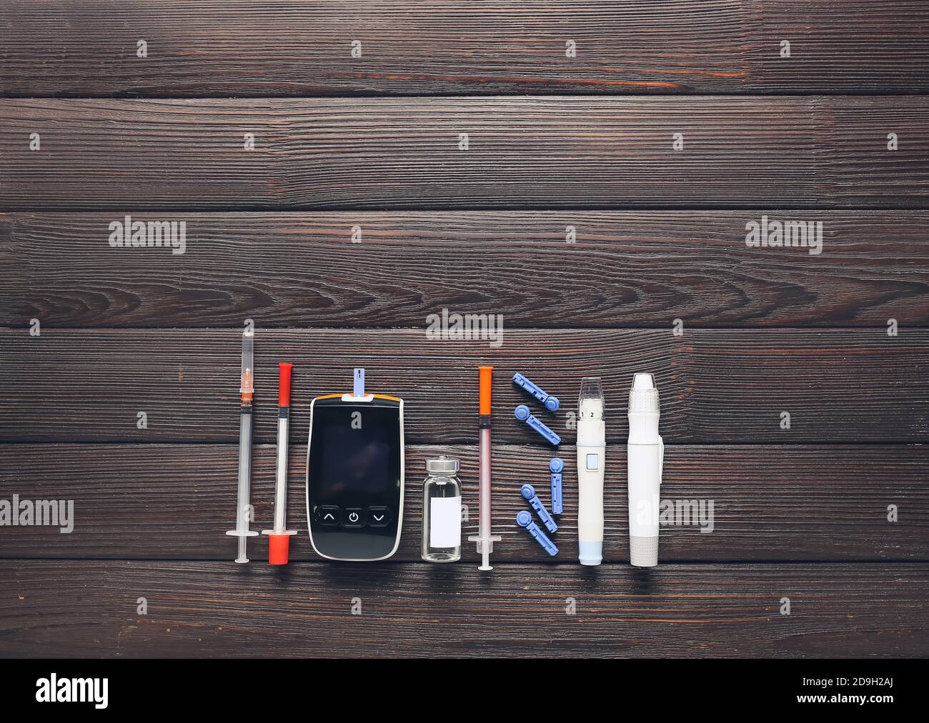 Glucometer, lancet pens, syringes and insulin on wooden background ...