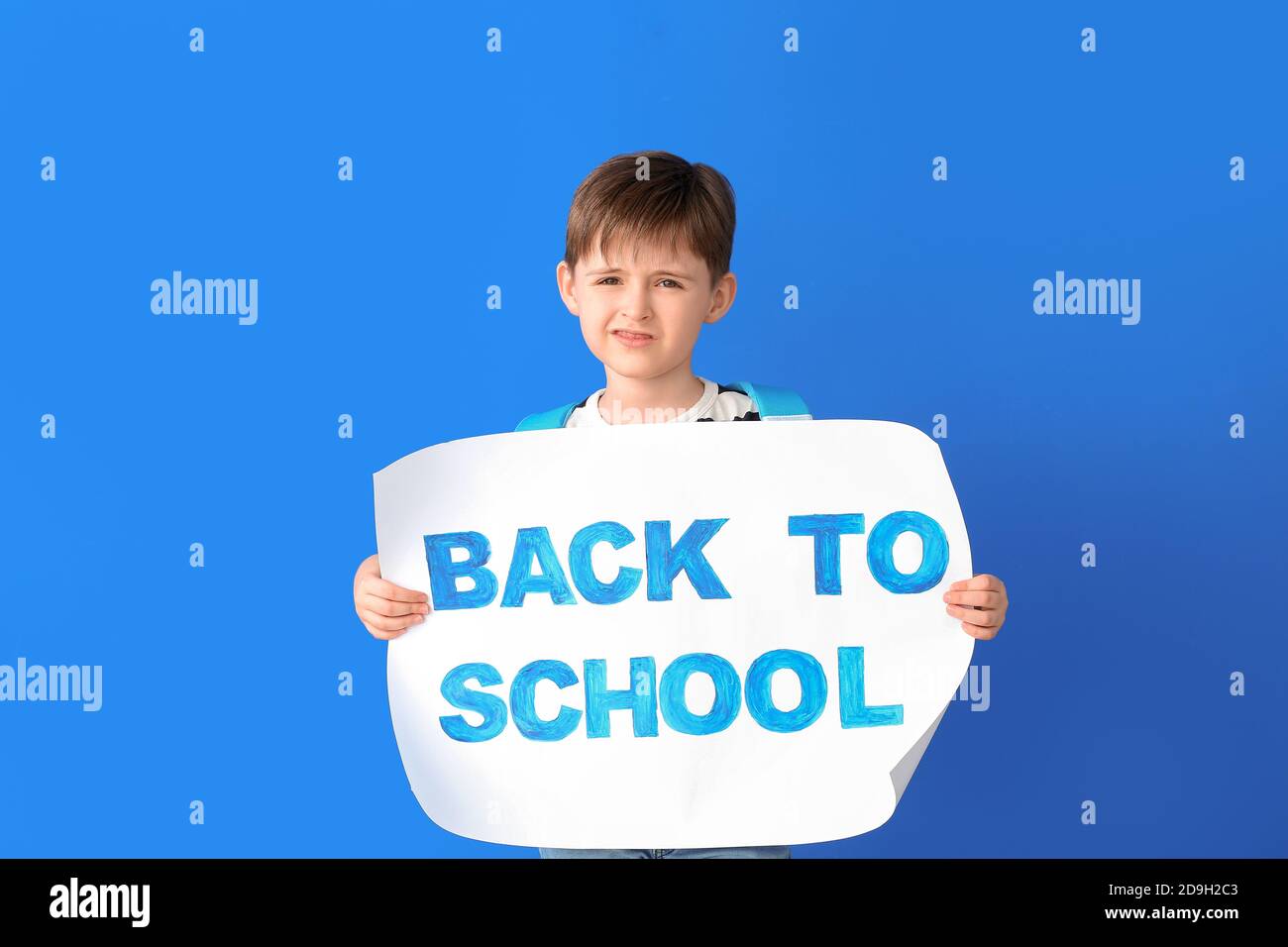 Little pupil holding placard with text BACK TO SCHOOL on color ...
