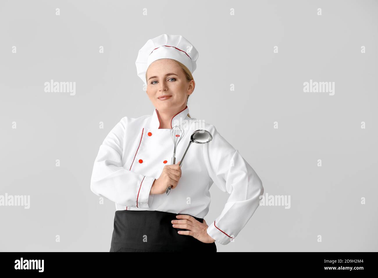 Mature female chef on grey background Stock Photo - Alamy