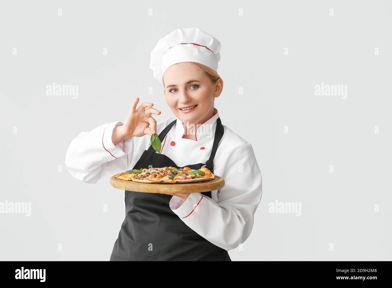 Mature female chef with tasty pizza on grey background Stock Photo - Alamy