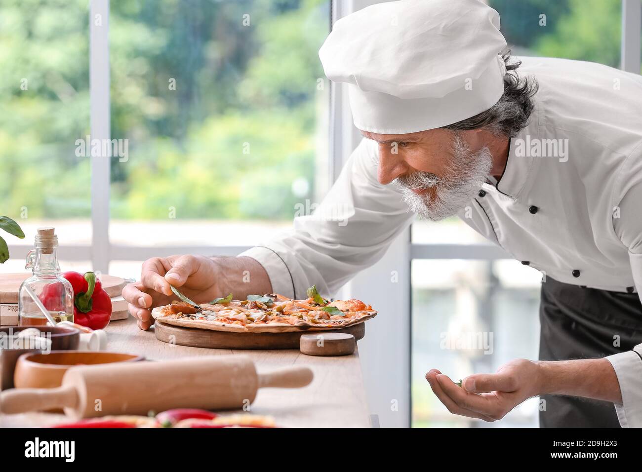 Mature male chef with tasty pizza in kitchen Stock Photo - Alamy