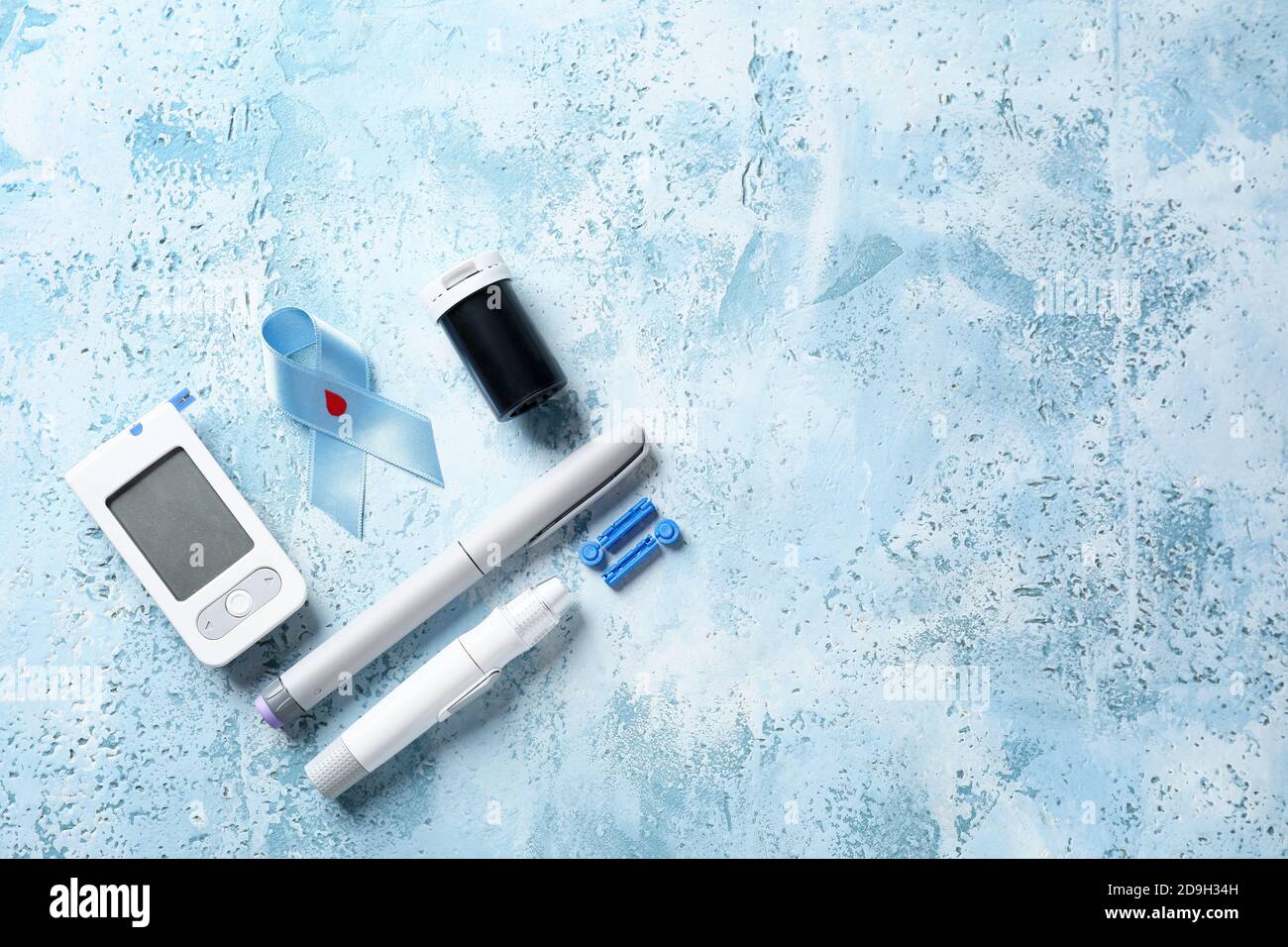 Awareness ribbon with glucometer, lancet pen and syringe on color ...