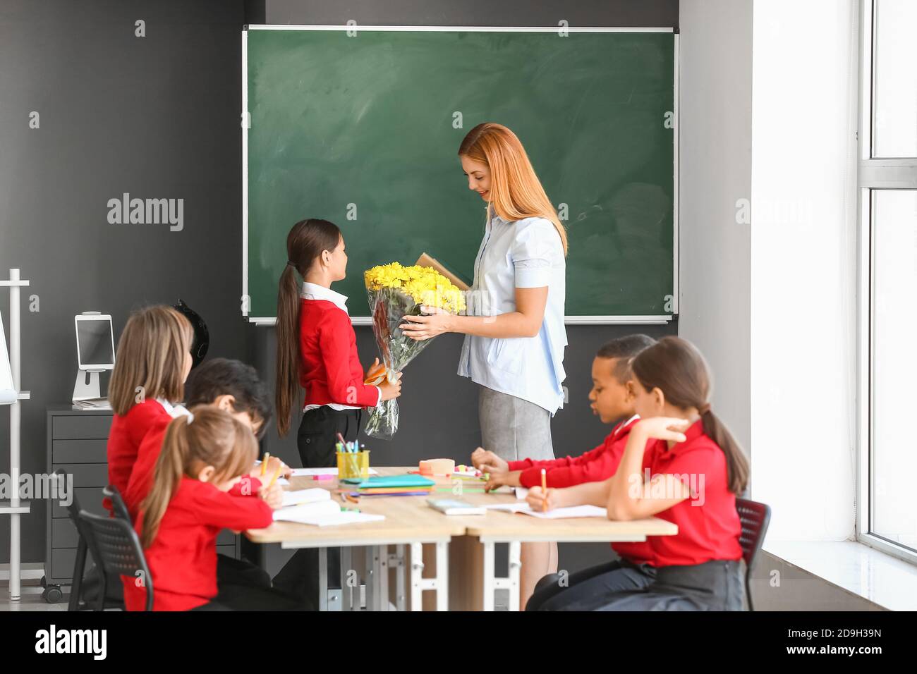 Schoolchildren greeting their teacher in classroom Stock Photo - Alamy